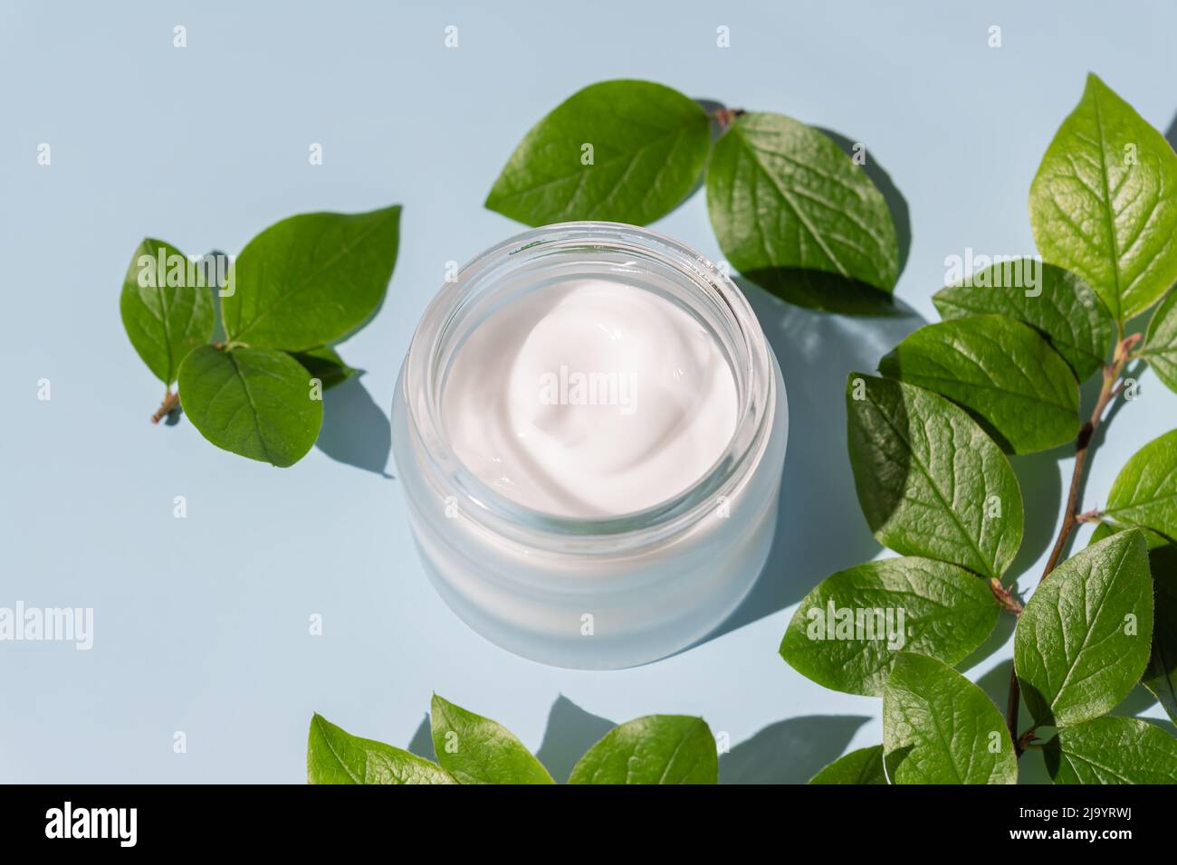 Top view of open jar with collagen firming anti age face cream on blue ...