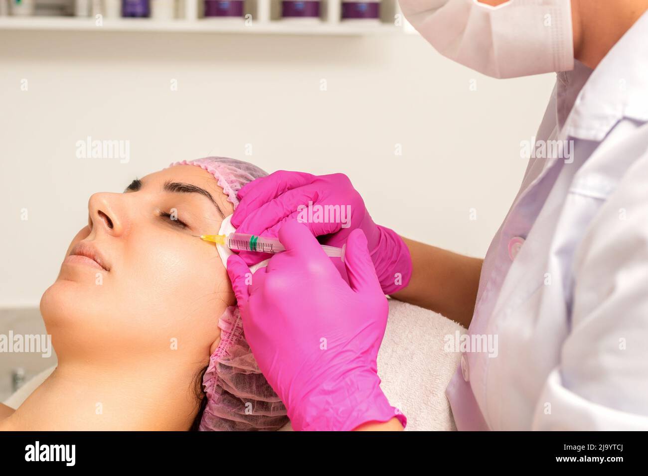 The young white woman is getting rejuvenating facial injections with ...