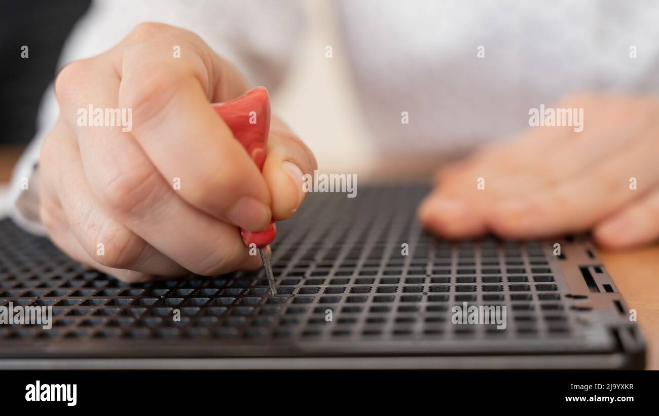 A woman uses a special stencil and stylus to write a letter in braille ...