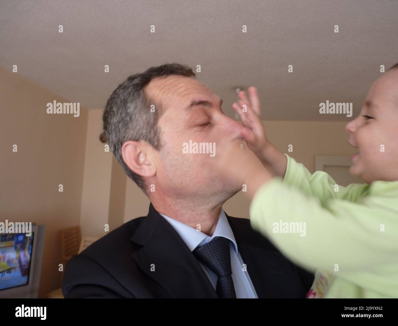 A handsome strong father in white is holding his cute little son in his ...