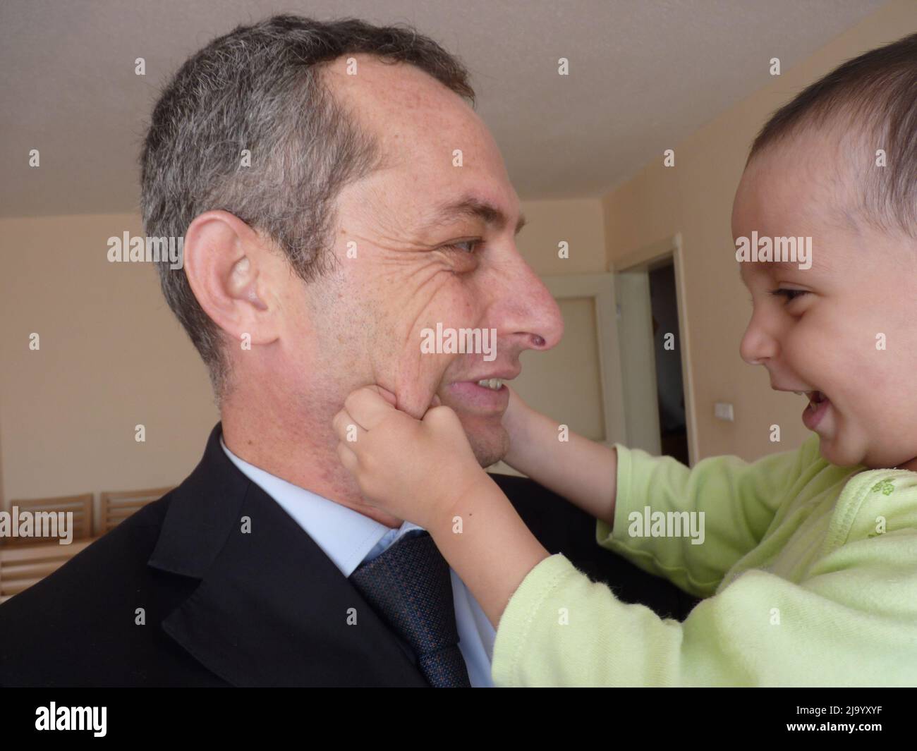 A handsome strong father in white is holding his cute little son in his ...