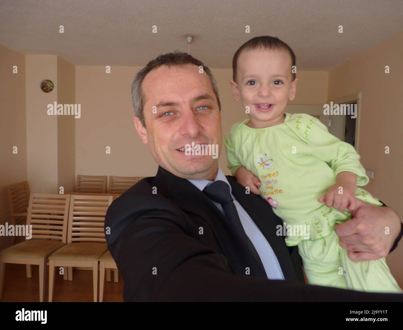 A handsome strong father in white is holding his cute little son in his ...