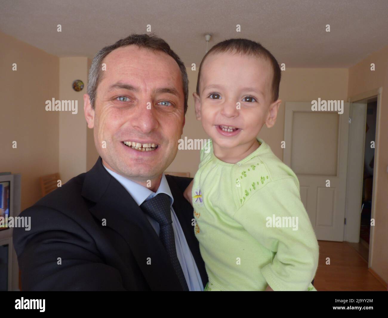 A handsome strong father in white is holding his cute little son in his ...