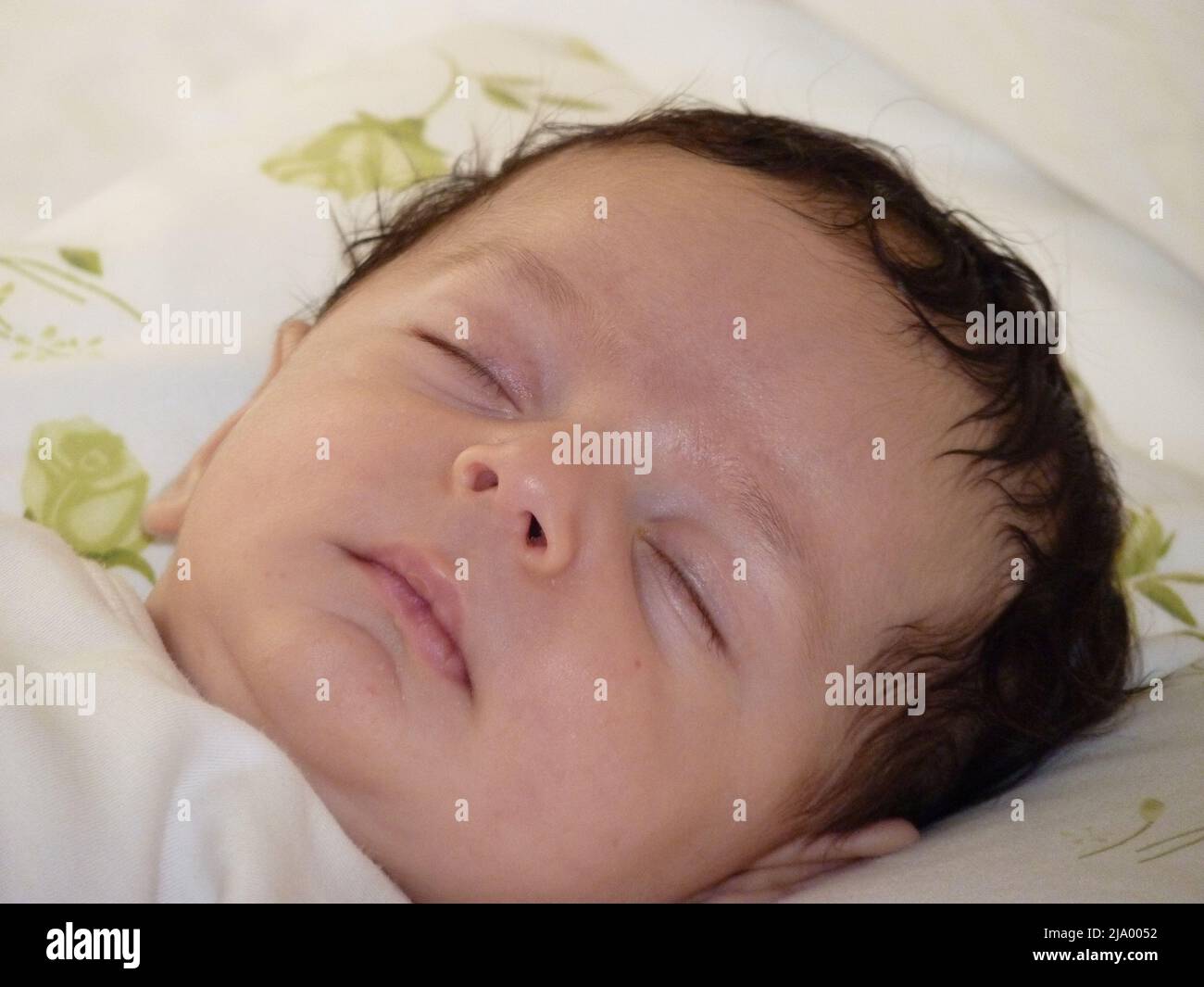 newborn baby sleeps in crib. He has gloves so he doesn't scratch his ...