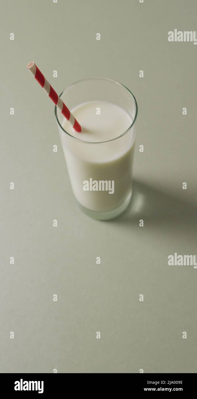 Vertical image of glass of milk with red and white straw on grey ...