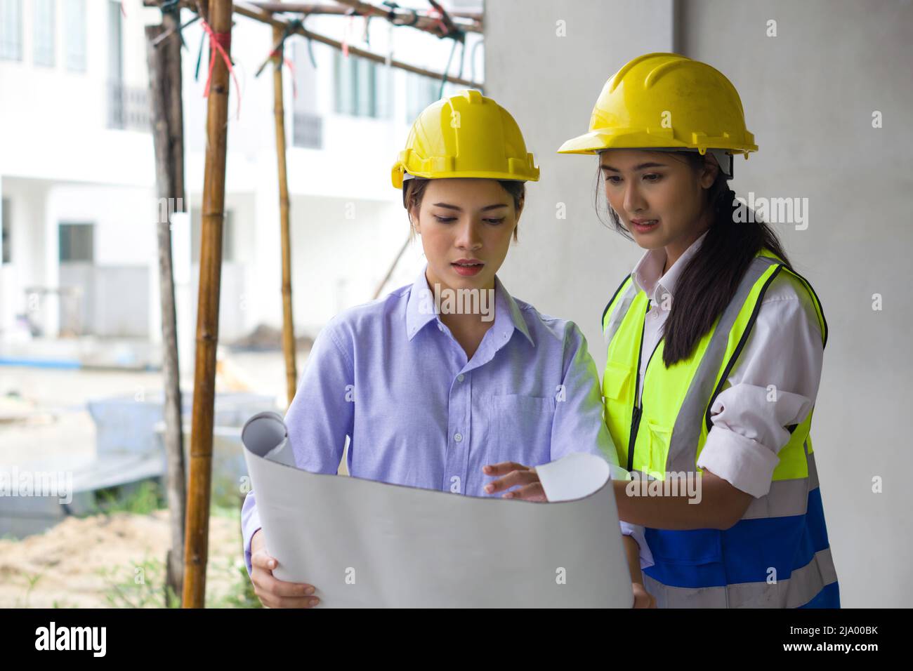Young engineer in a construction helmet and safety vest explaining to ...
