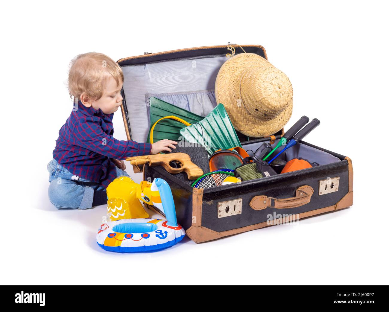 A little boy checks a suitcase with travel equipment, on white ...