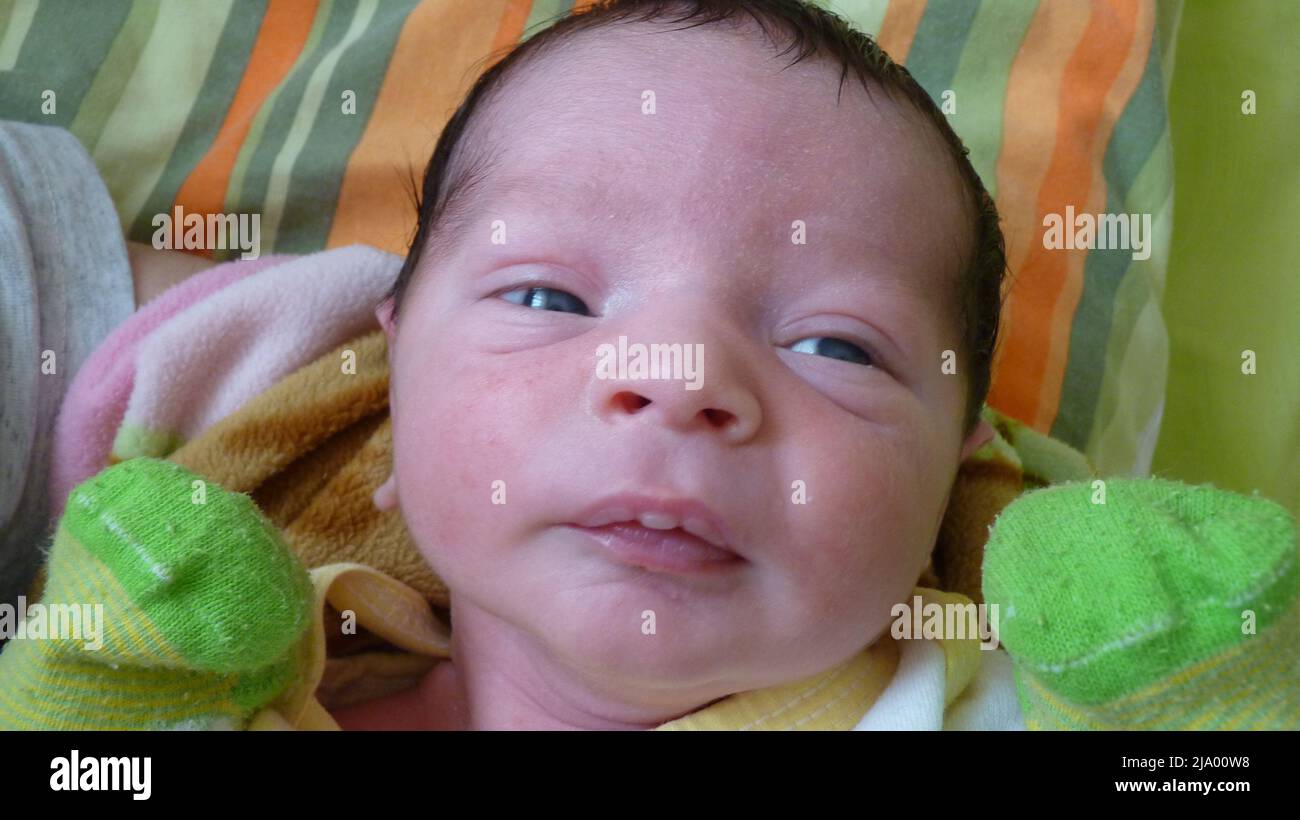newborn baby sleeps in crib. He has gloves so he doesn't scratch his ...