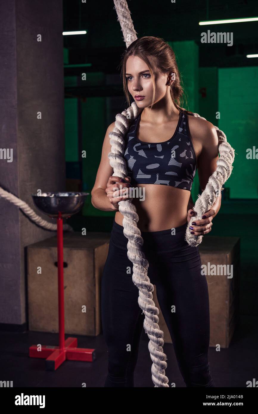 Shot of an attractive female crossfit athlete with a rope at the gym ...