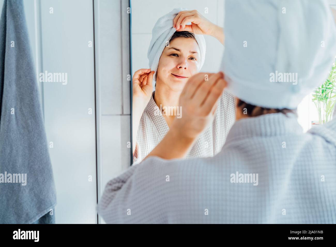 Calm smiling mixed race woman in spa bathrobe and towel relaxing after ...