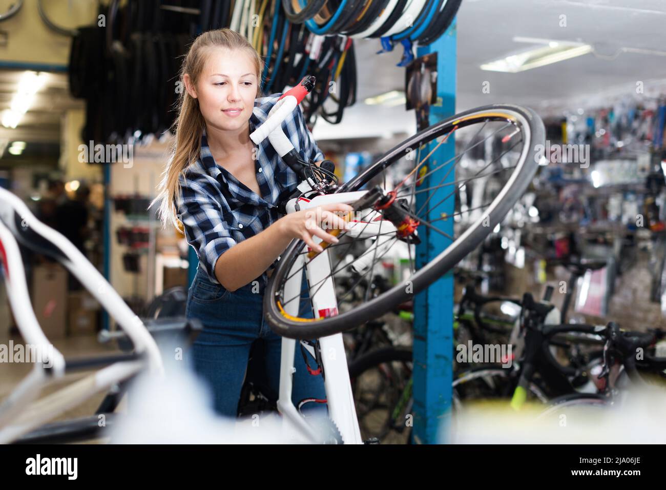 Woman master is fixing wheel of bicycle Stock Photo - Alamy