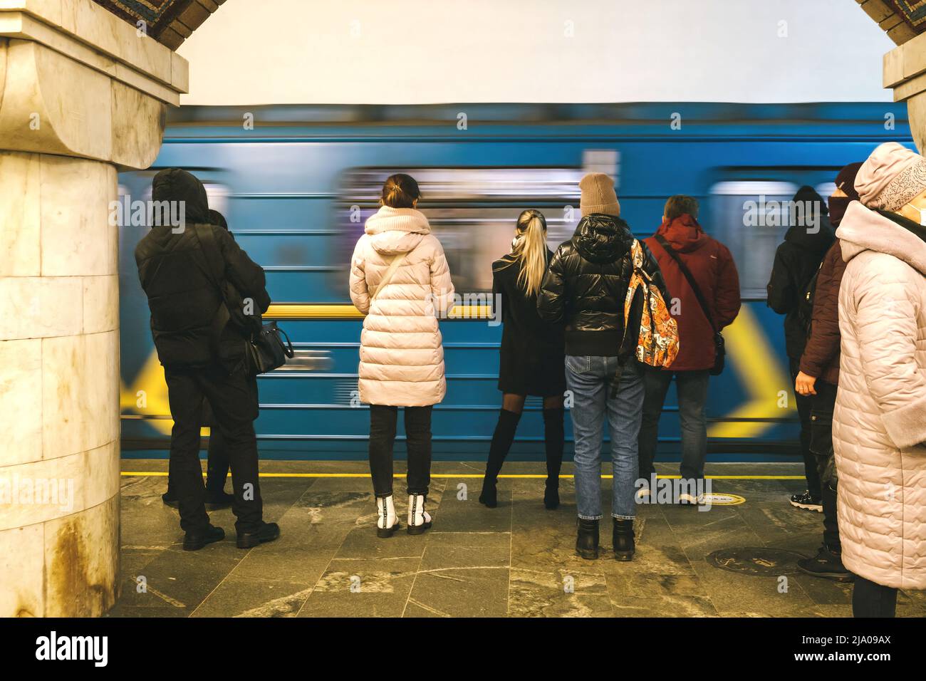 People on a subway platform on the background of a passing train ...