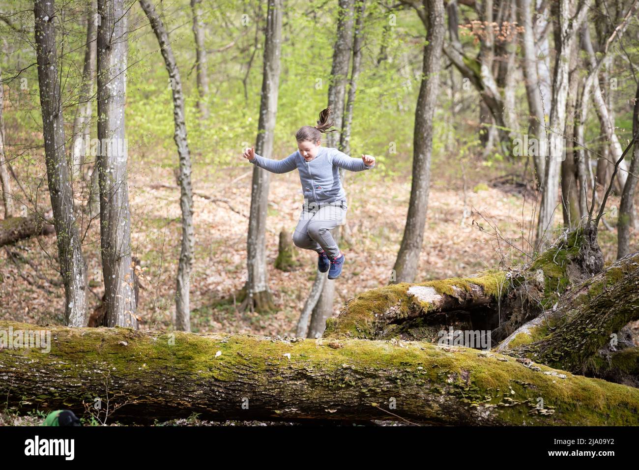 Little girl having fun, jumping in the forest. The concept of outdoor ...