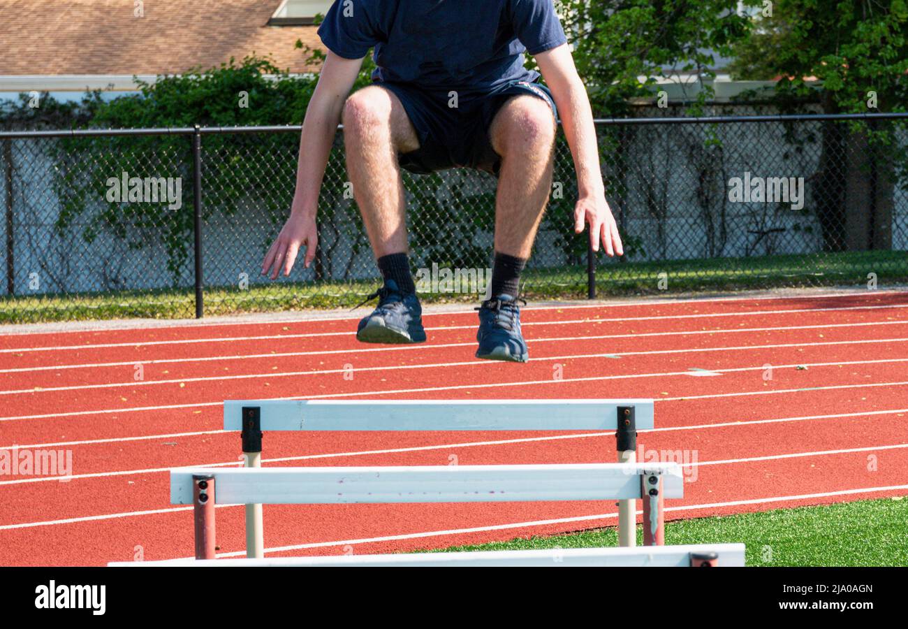A high school track runner is jumping over hurdles during spring track ... A high school track runner is jumping over hurdles during spring track ...