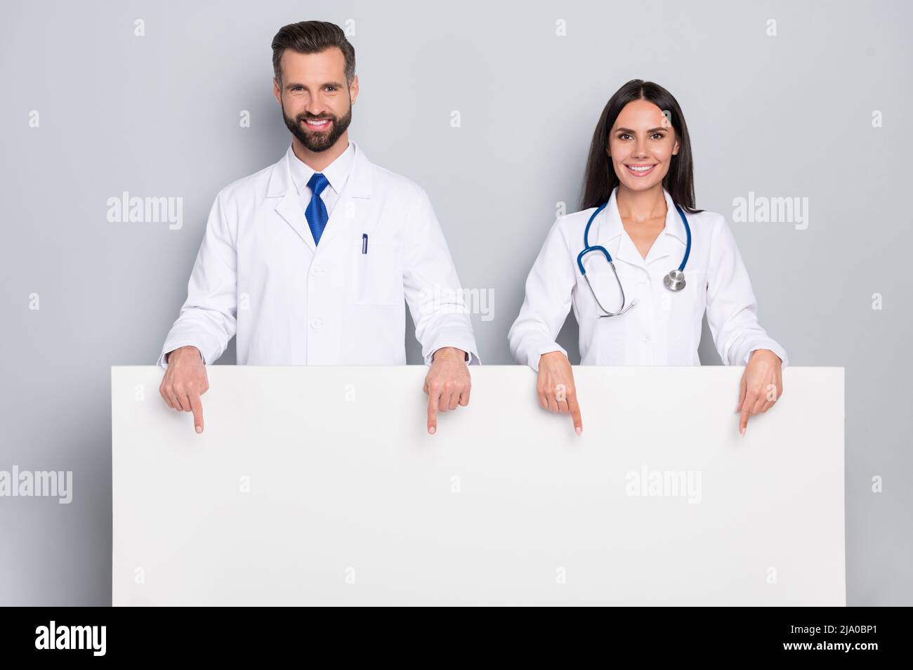 Portrait of two attractive cheerful medics demonstrating big poster ...