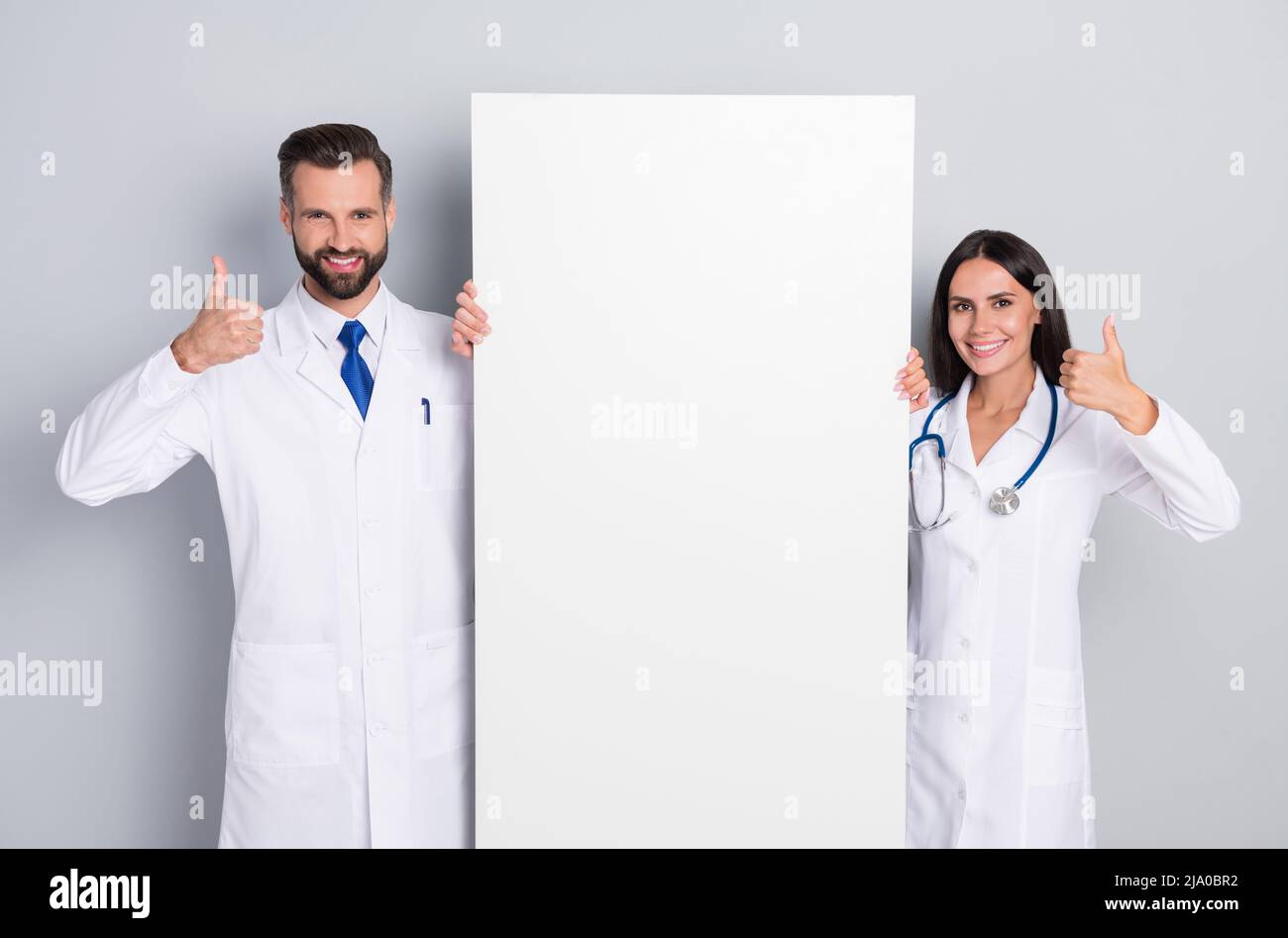 Portrait of two attractive cheerful medics holding big poster copy ...