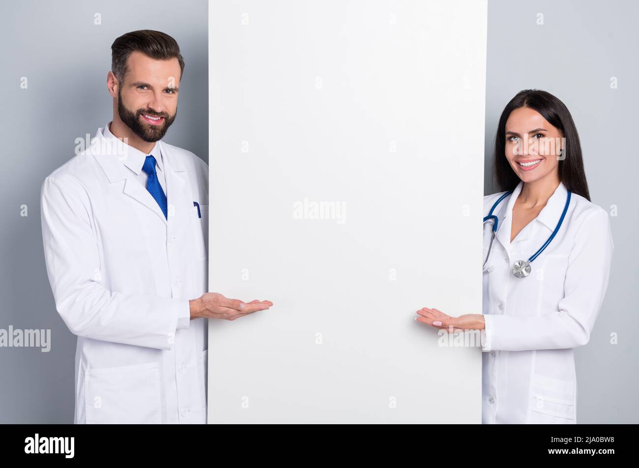Portrait of two attractive cheerful medics demonstrating blank space ...
