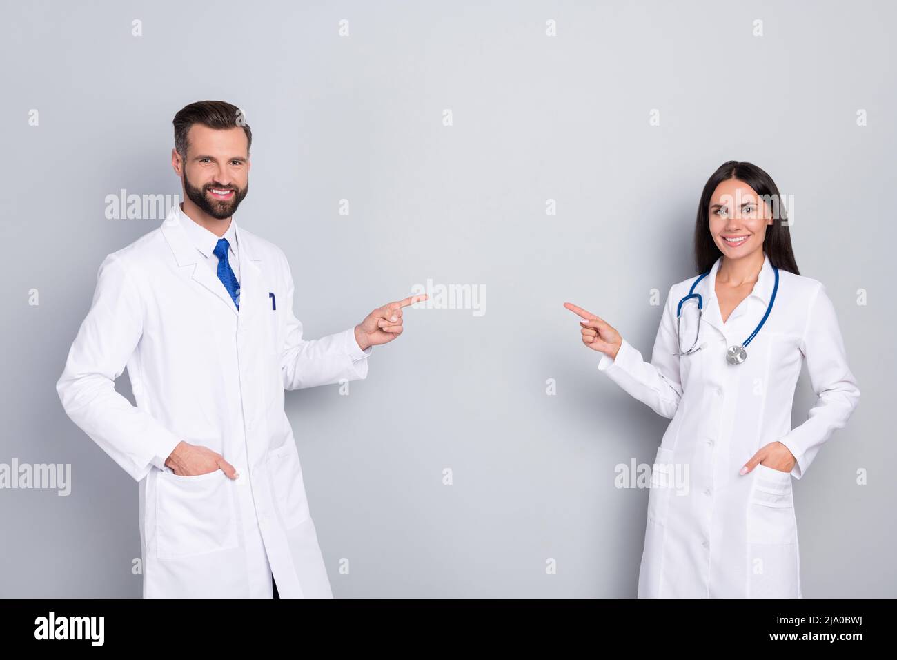 Portrait of two attractive cheerful medics showing copy space insurance ...