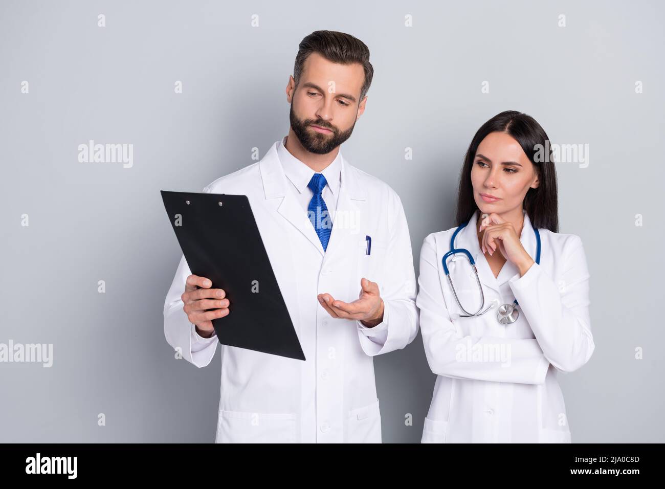 Portrait of two attractive focused skilled smart doctors reading ...