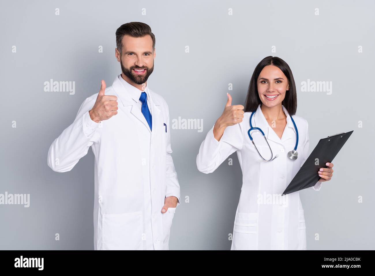 Photo of intelligent smiling two docs dressed white coats holding ...