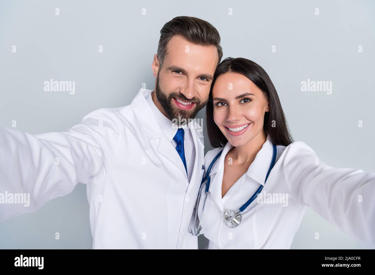 Self-portrait of two attractive cheerful medics bonding practicing team ...