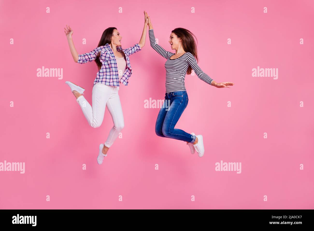 Full length portrait of two excited active people jumping hand give ...
