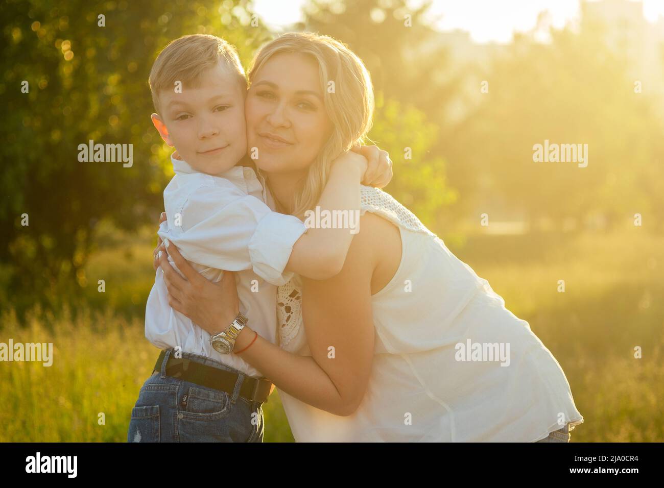 happy cute little boy hugging beautiful mother in the park against the ...