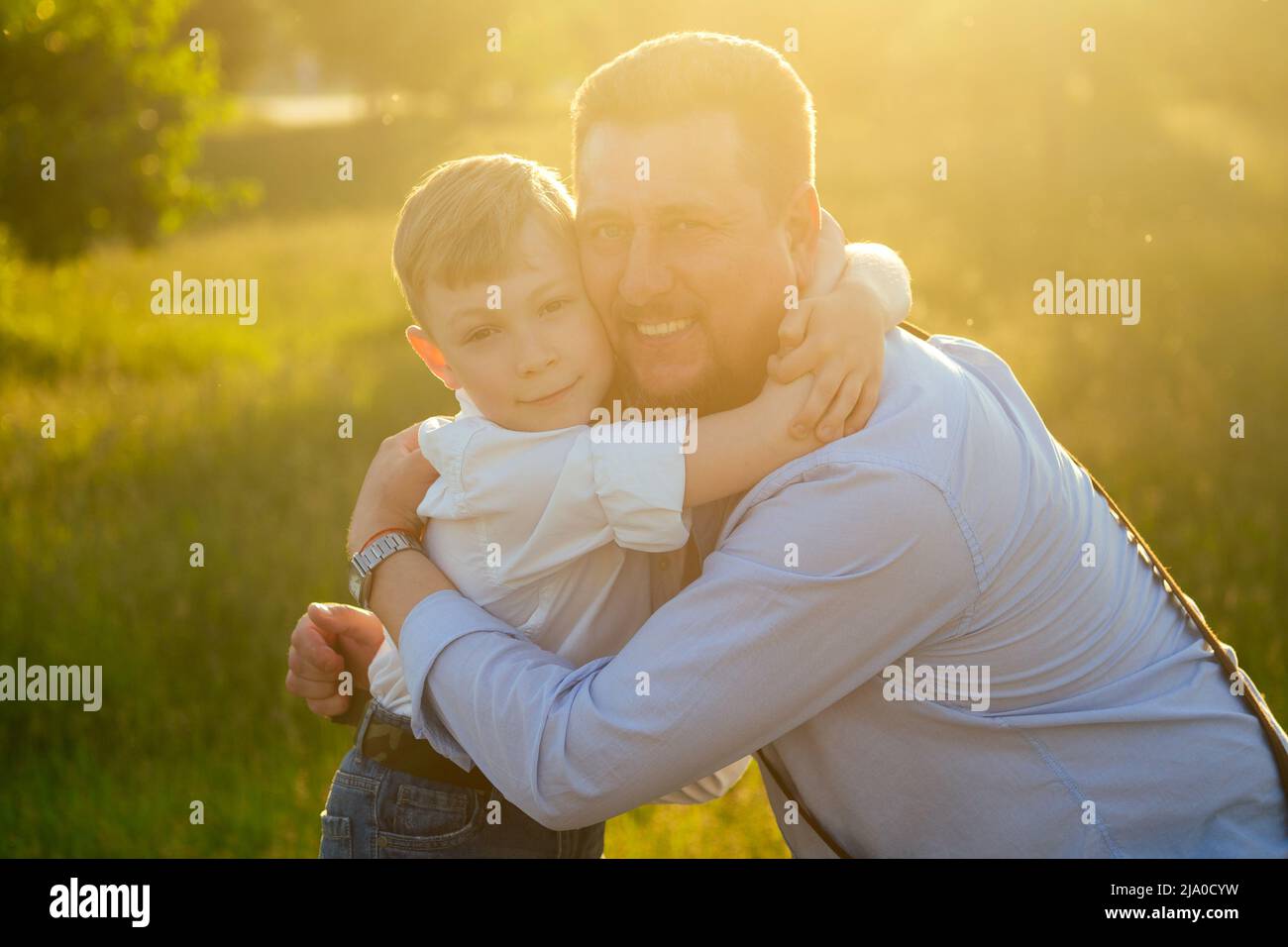 happy cute little boy hugging father in the park against the background ...