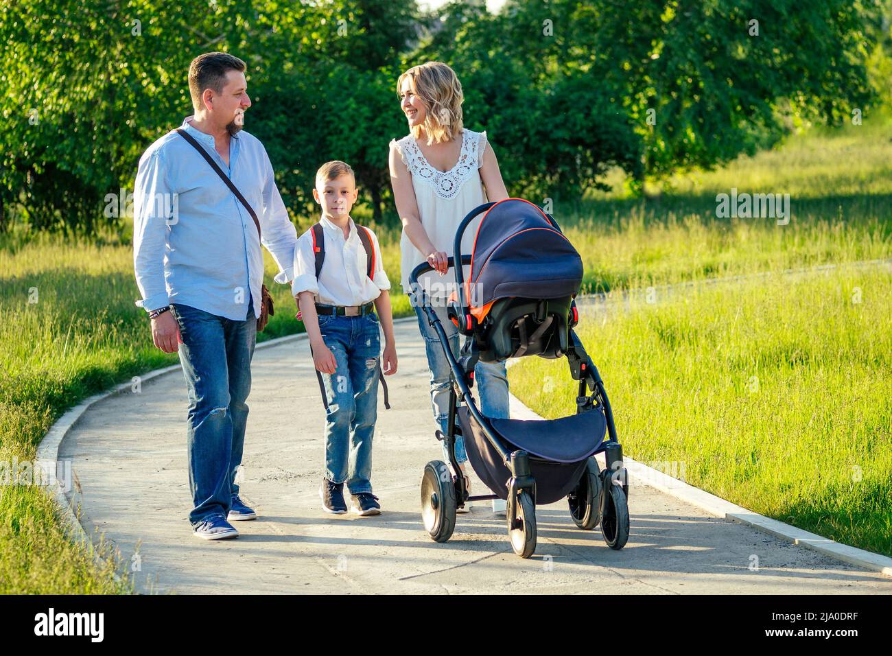 active big family father, mother, son and baby in stroller walking in ...