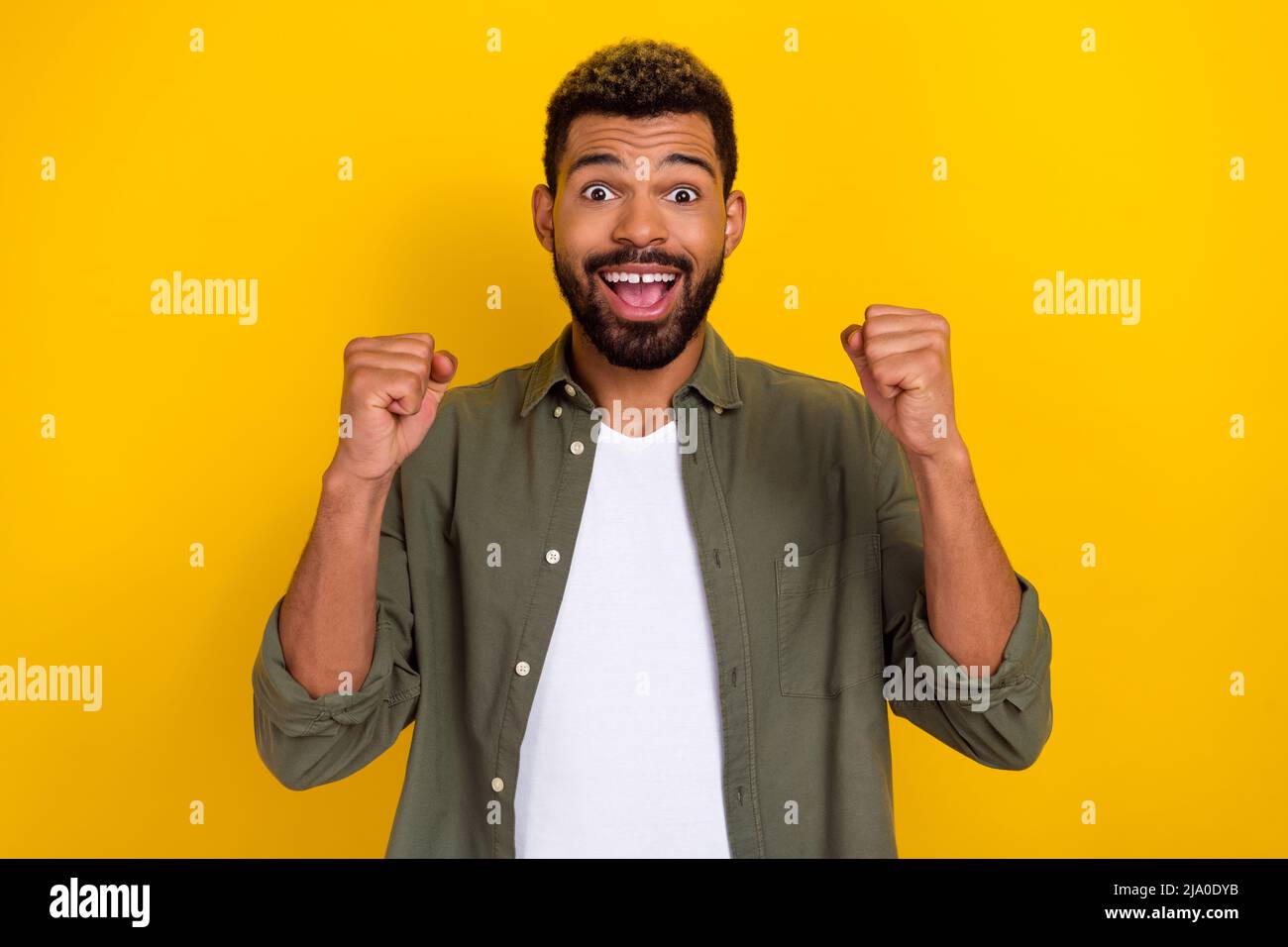 Photo of cute excited guy dressed green shirt screaming rising fists ...
