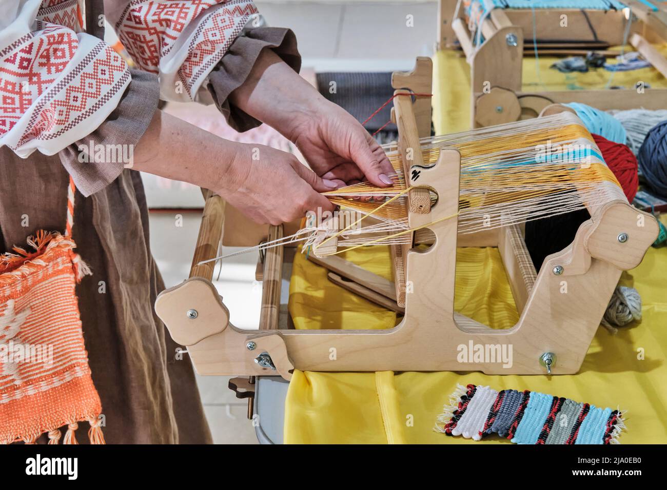 Woman's hands threading colorful warp threads on table loom Stock Photo ...