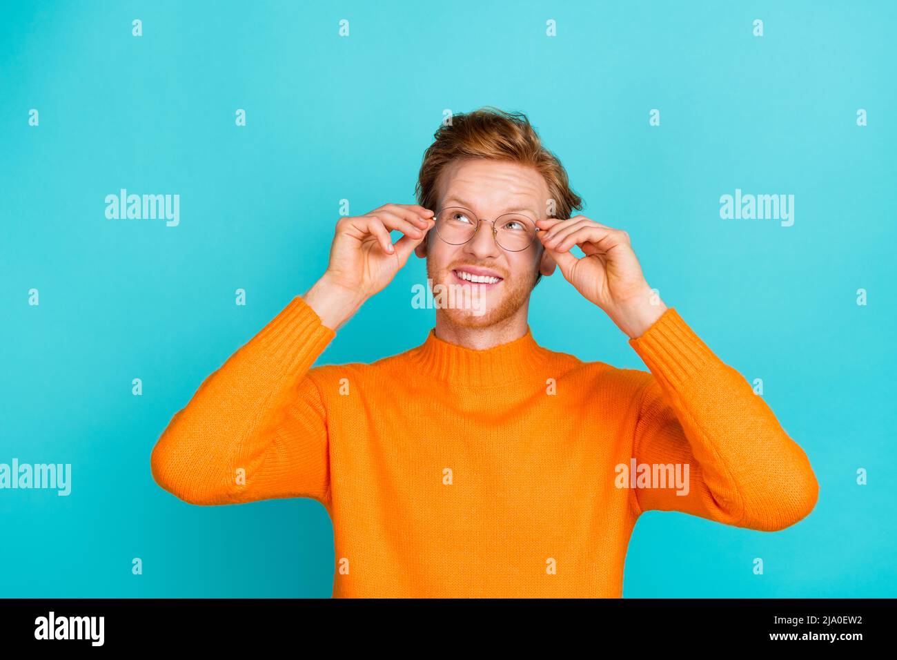 Photo of dreamy cute guy dressed orange sweater arms eyewear looking ...