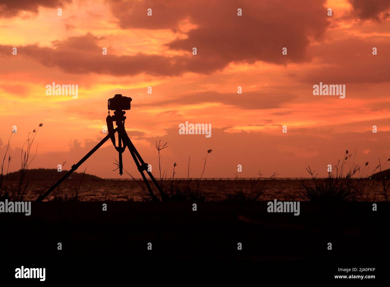 photo camera with tripod At sunset, dusk, colors and shapes of clouds ...