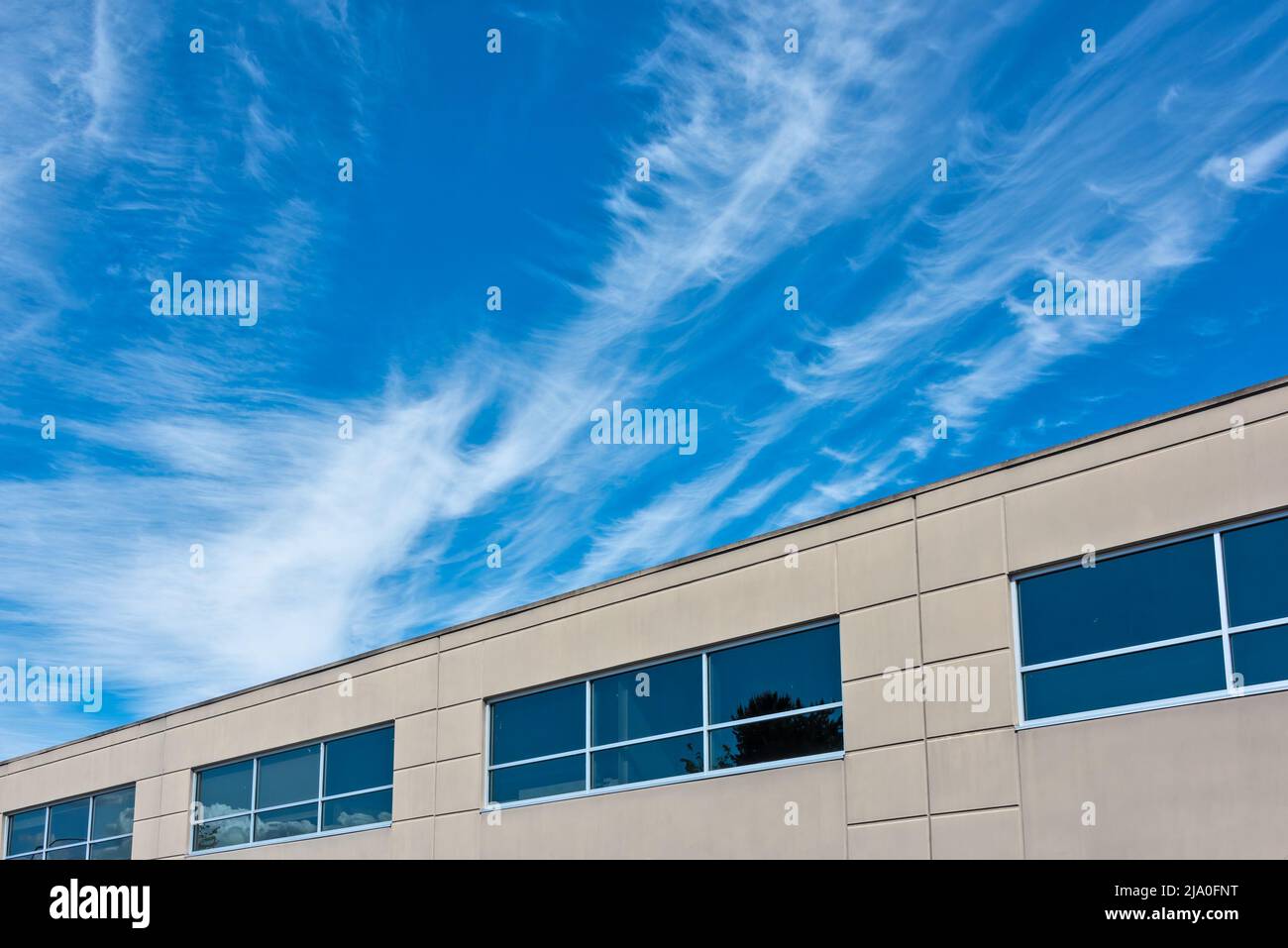 Top of the office building with windows on blue and cloudy sky ...