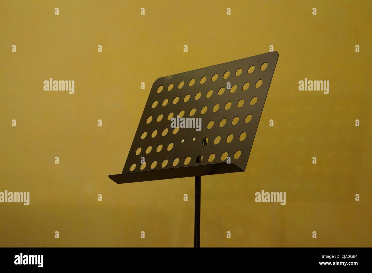 Metal music stand top against an ochre stucco wall Stock Photo - Alamy
