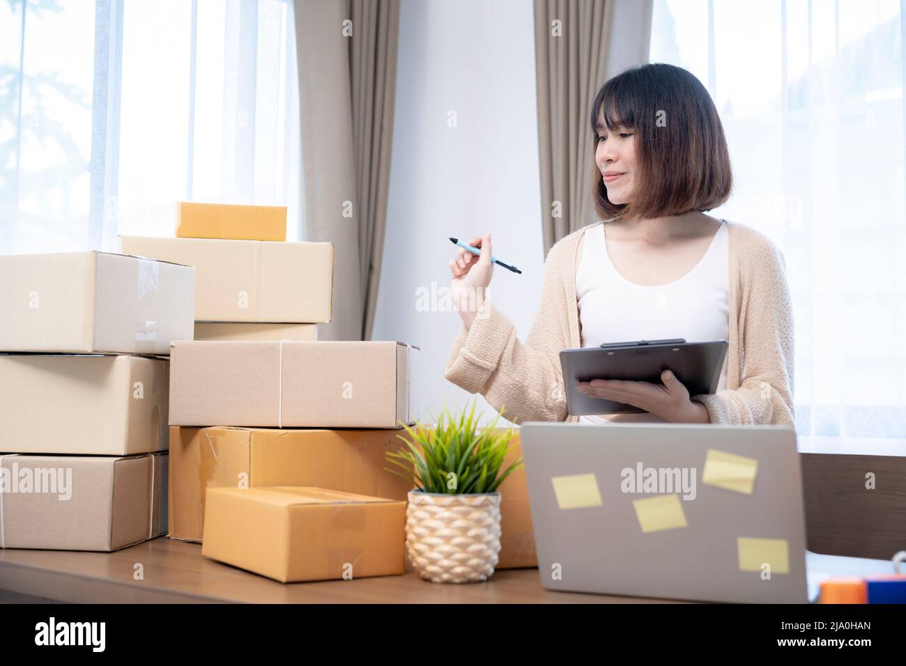 Young Asian female counting purchase order parcel before sending to ...