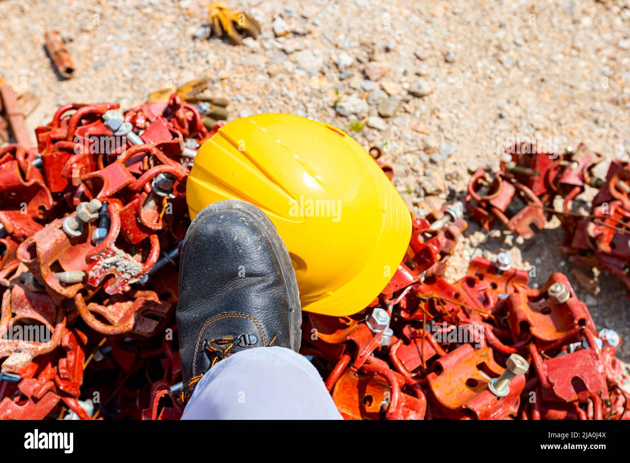 View from above on worker who wears safety shoe and tramples on pile ...