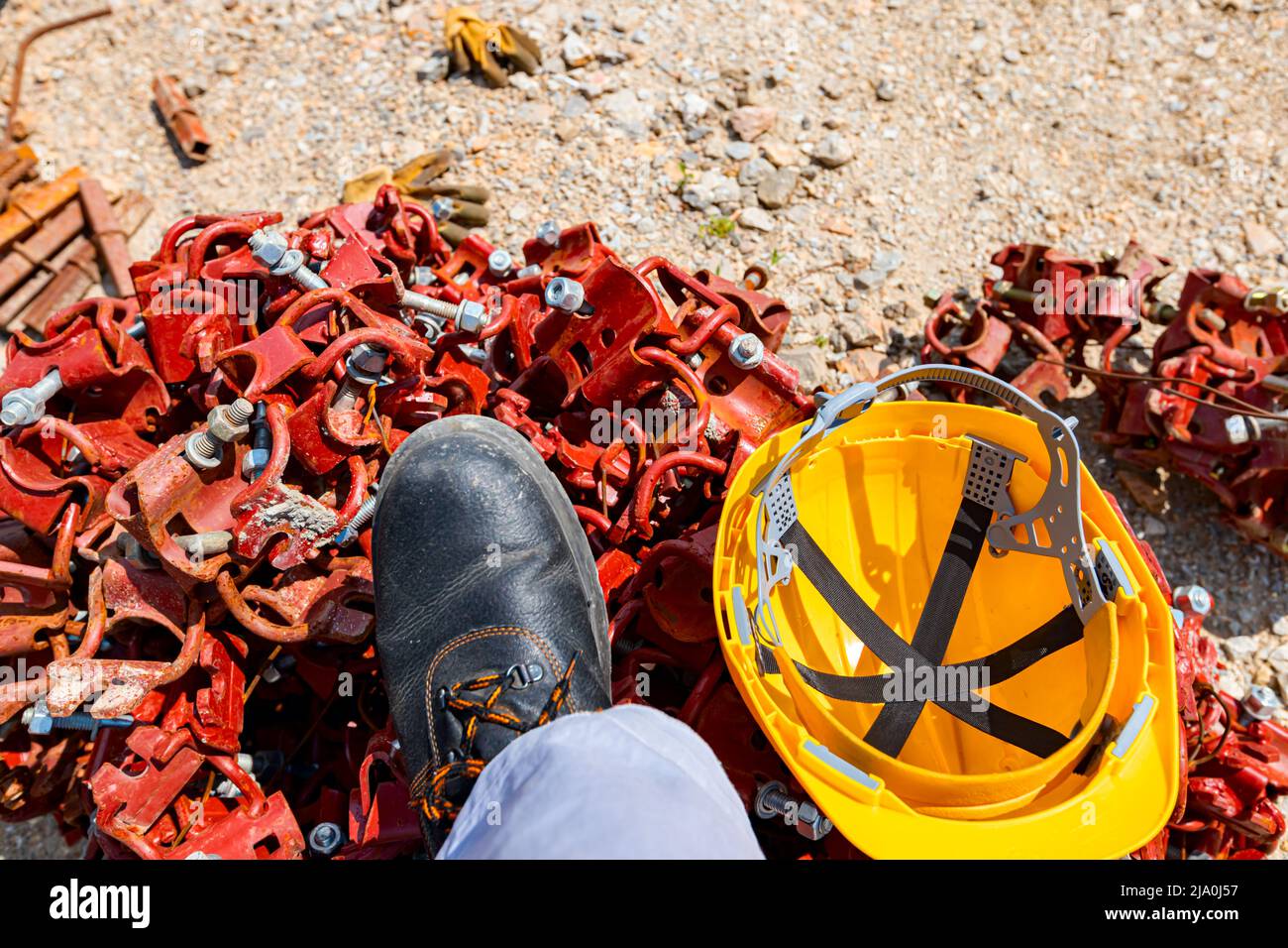 View from above on worker who wears safety shoe and tramples on pile ...