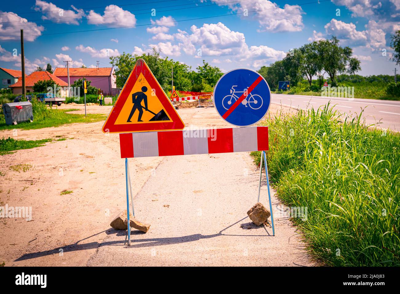 Two signs are set on the road at construction site, triangle sign, work ...