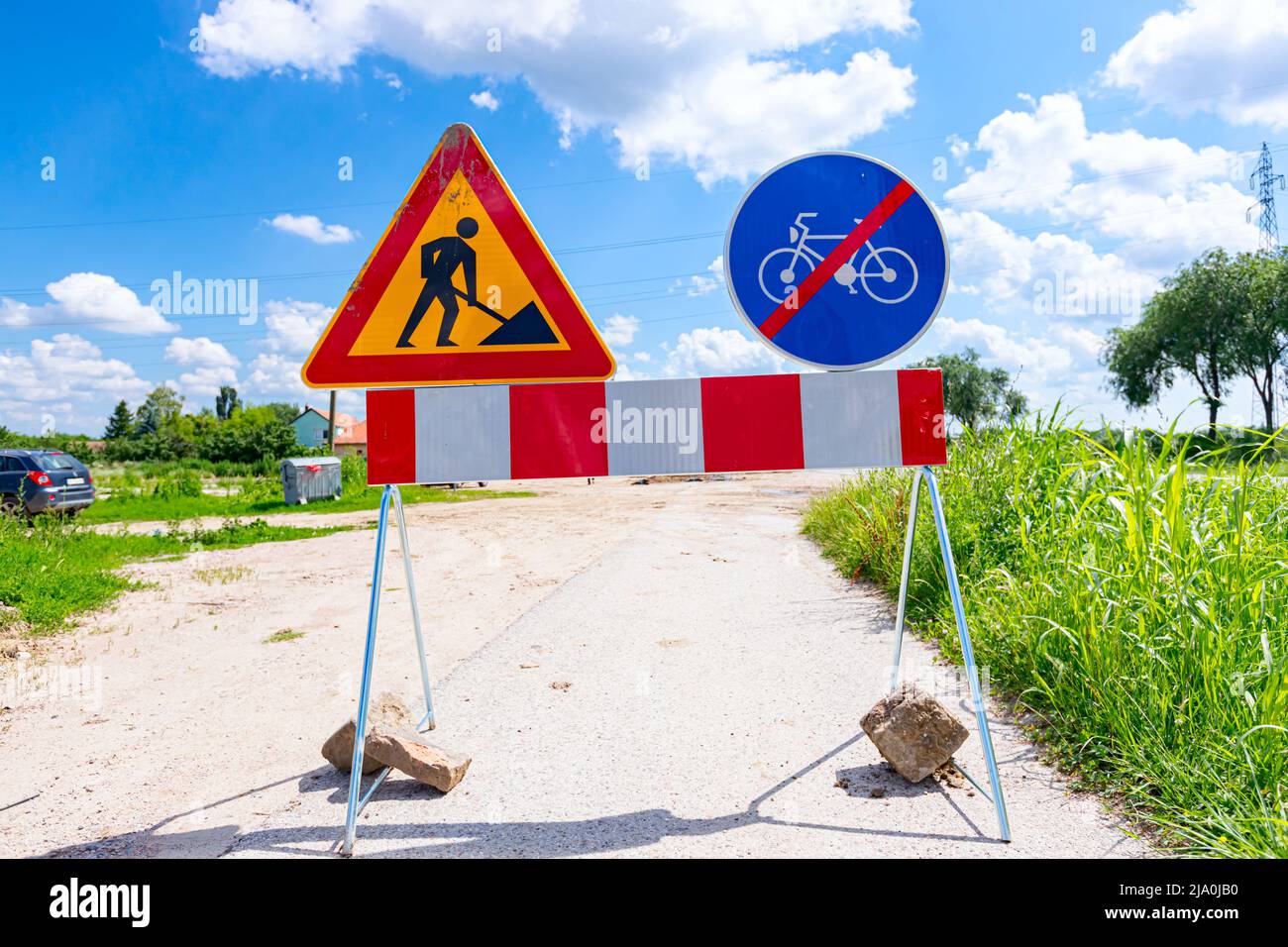 Two signs are set on the road at construction site, triangle sign, work ...