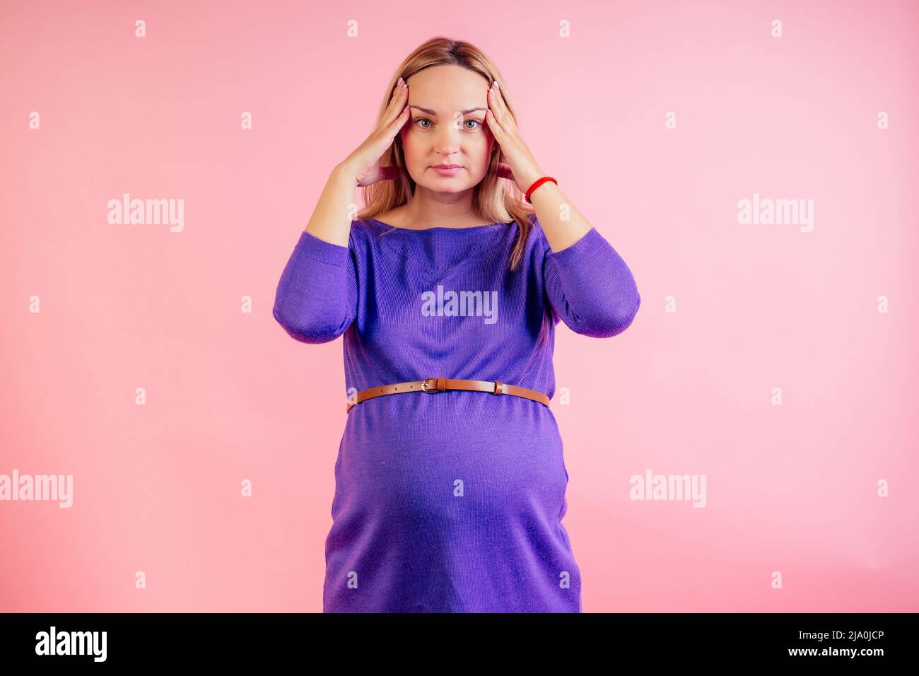 Beautiful blonde pregnant sad woman in a violet dress with big baby ...