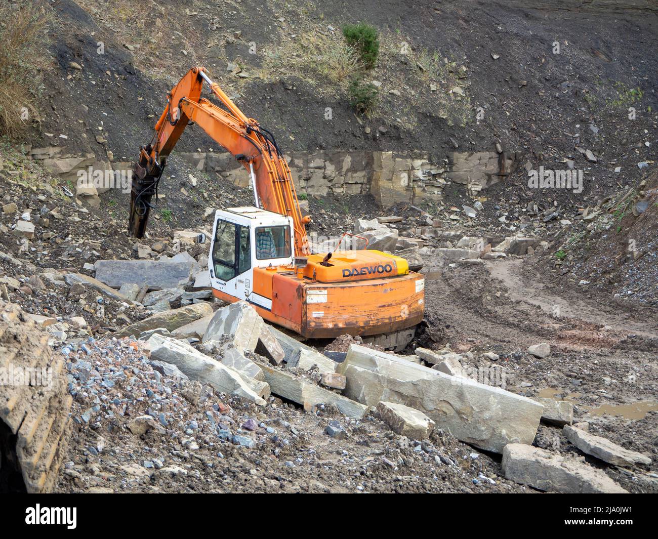 Orange digger in the bottom of the quarry Stock Photo - Alamy