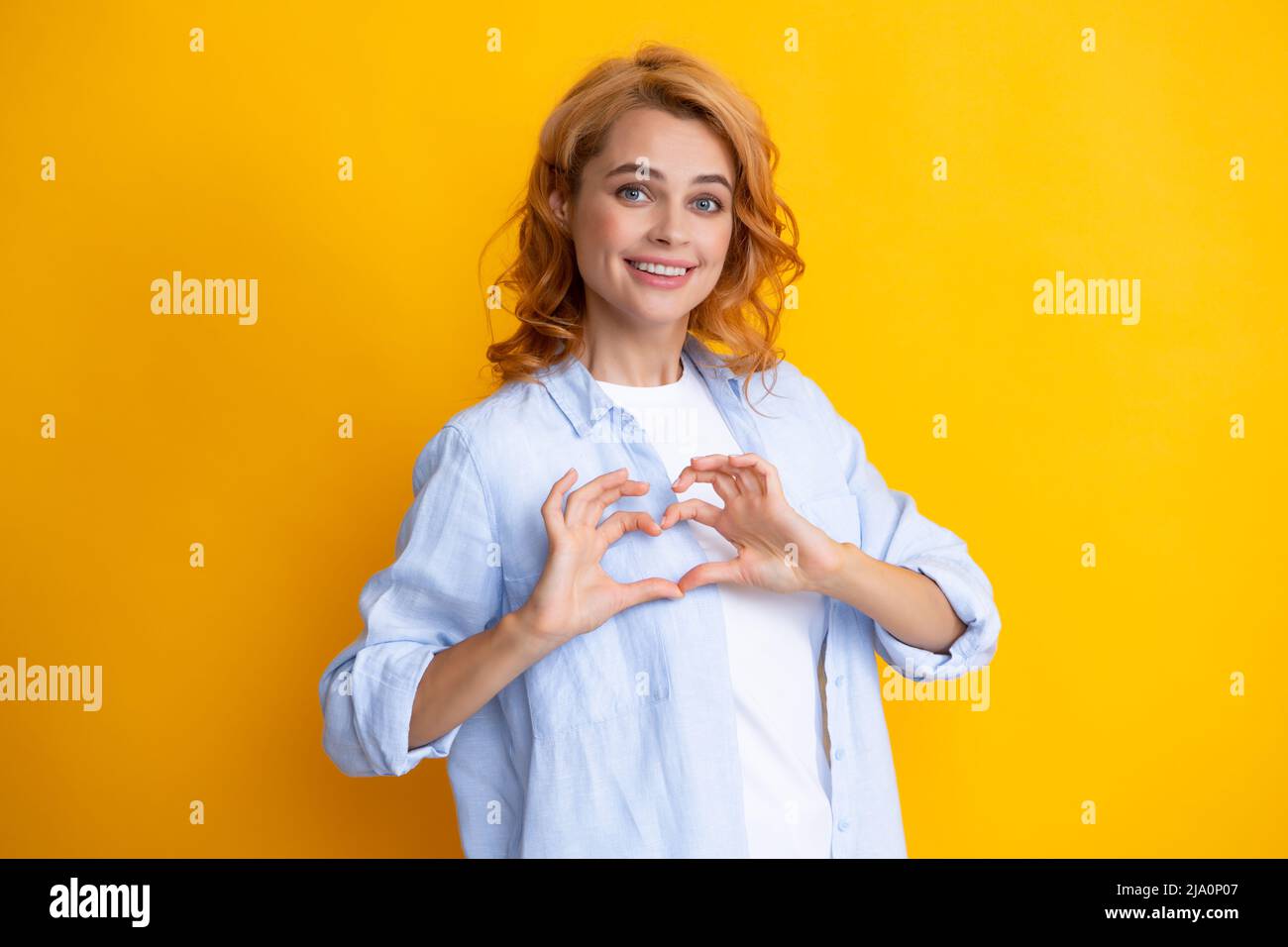 Pretty romantic young woman making a heart gesture, showing love and ...