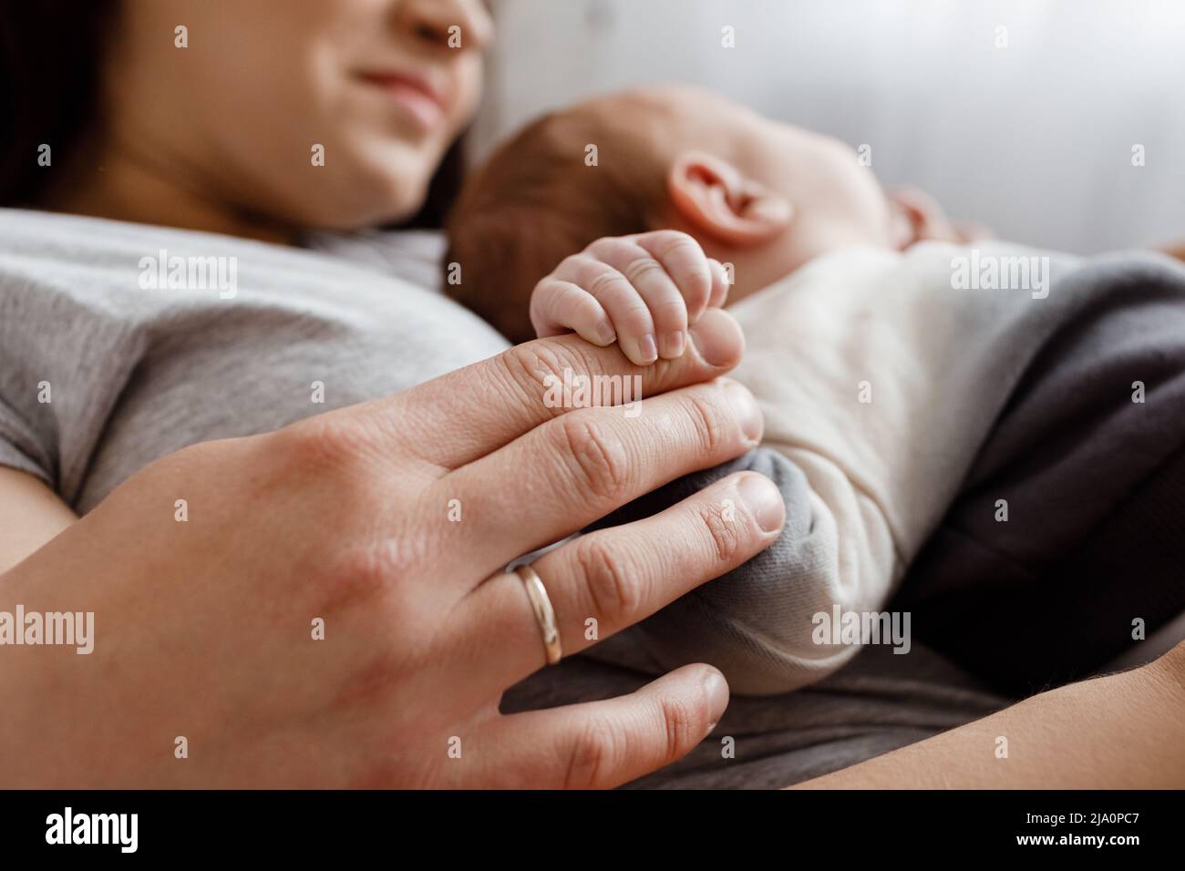 Young parents holding tiny hand of baby. Close up of mom, dad and baby ...