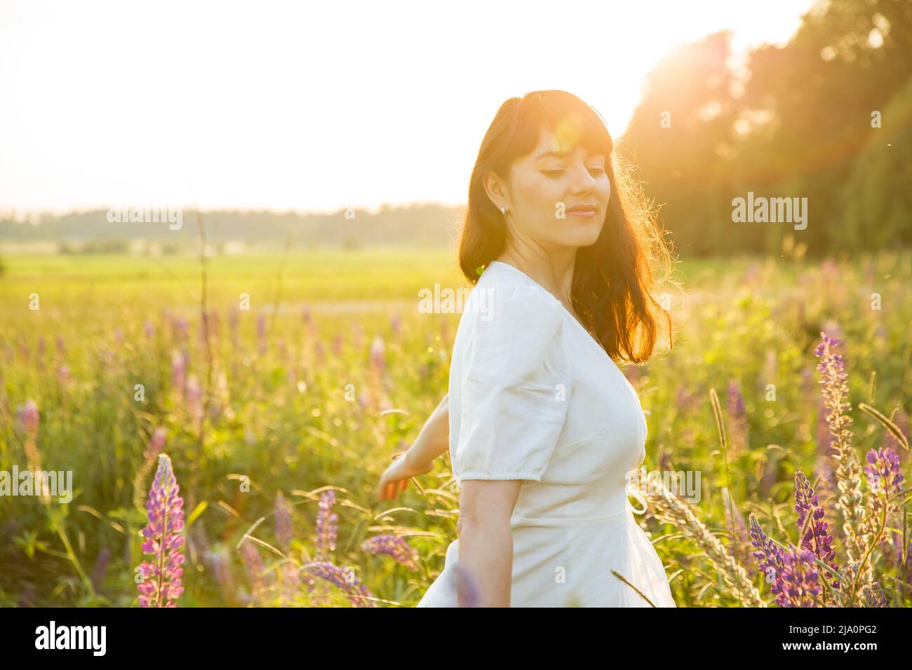 Beautiful woman in white sundress enjoying the summer nature. Picking ...