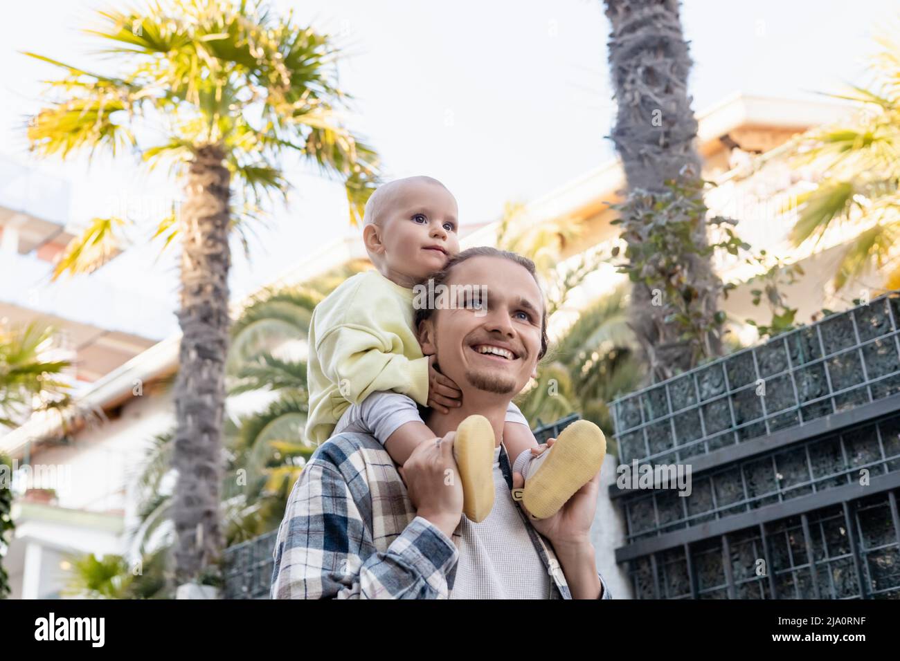 Low angle view of happy father carrying baby on shoulders on urban street in Treviso Stock Photo ...