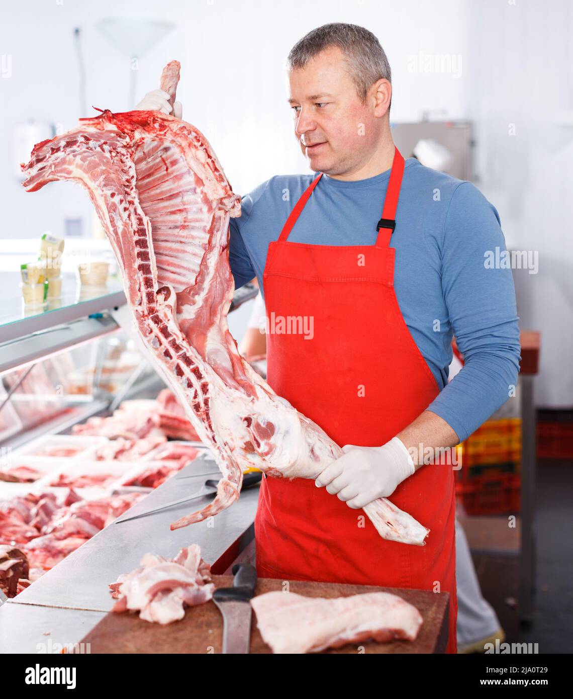 Smiling man splitting and showing of pig carcass Stock Photo - Alamy