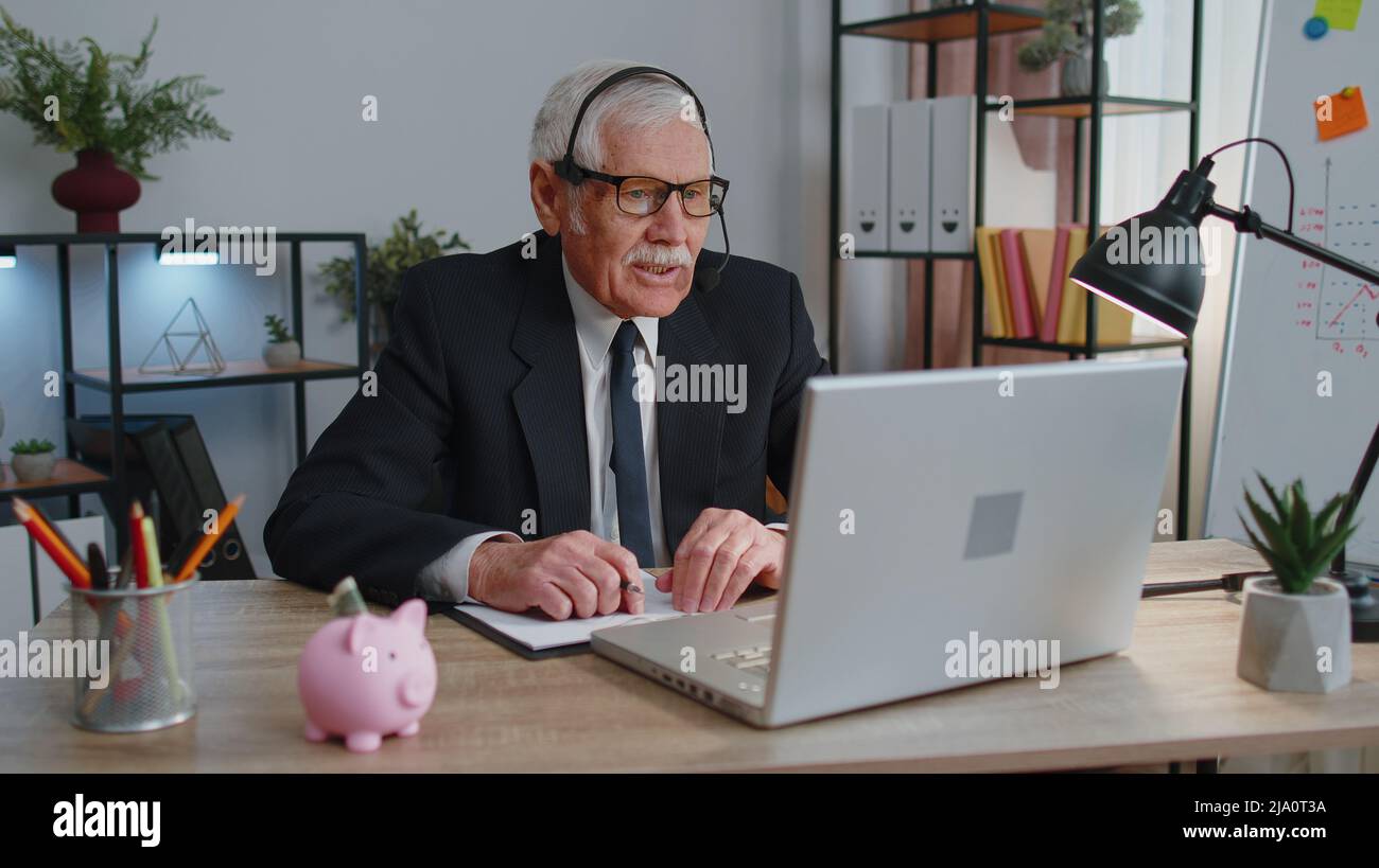 Senior businessman in headphones making conference video call on laptop ...
