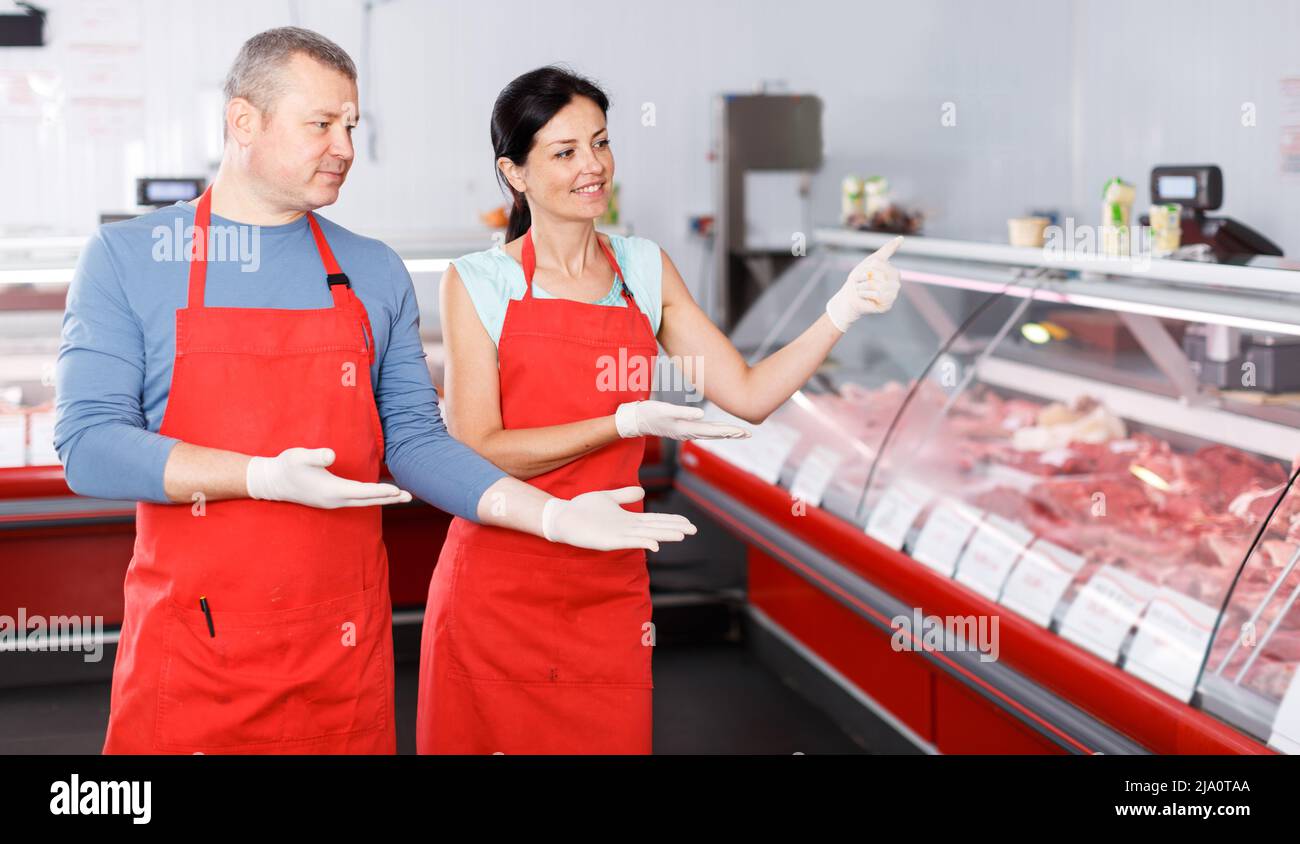 Man and woman seller offering products in shop Stock Photo - Alamy