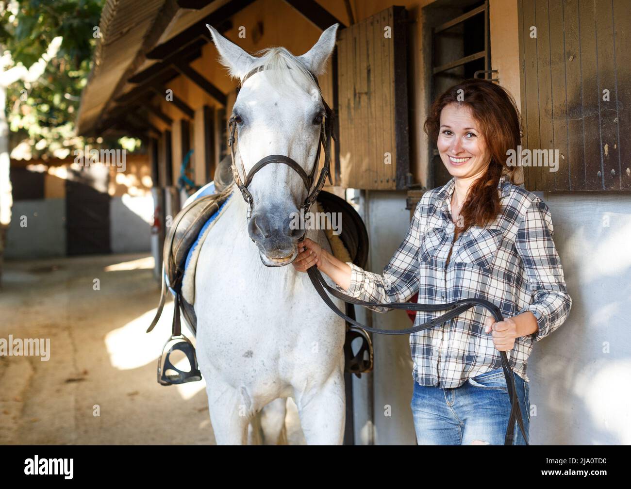 Female farmer standing with white horse at stable outdoor Stock Photo ...